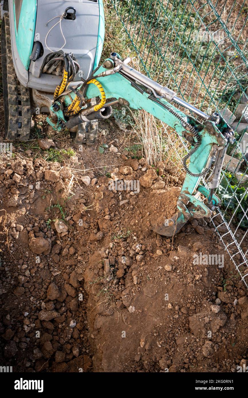 Mini excavator digs a trench to lay pipes. Close up of an excavator ...