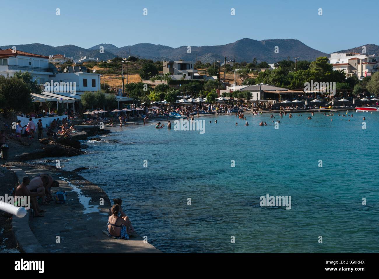 A view of people enjoying a summer day at the beach under the blue ...