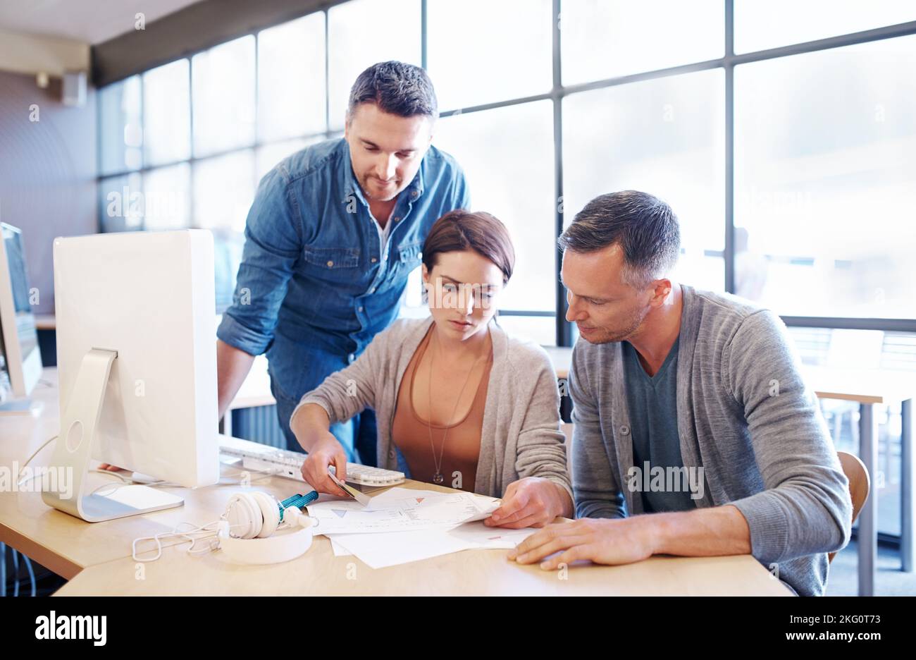 Putting their heads together. three coworkers going through paperwork ...
