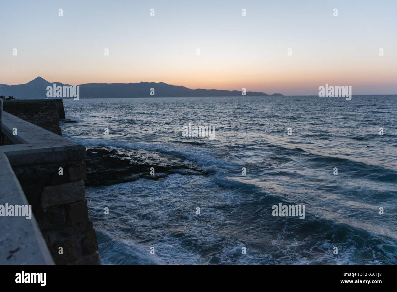 The sea waves reaching the waterside stone wall at sunset Stock Photo ...