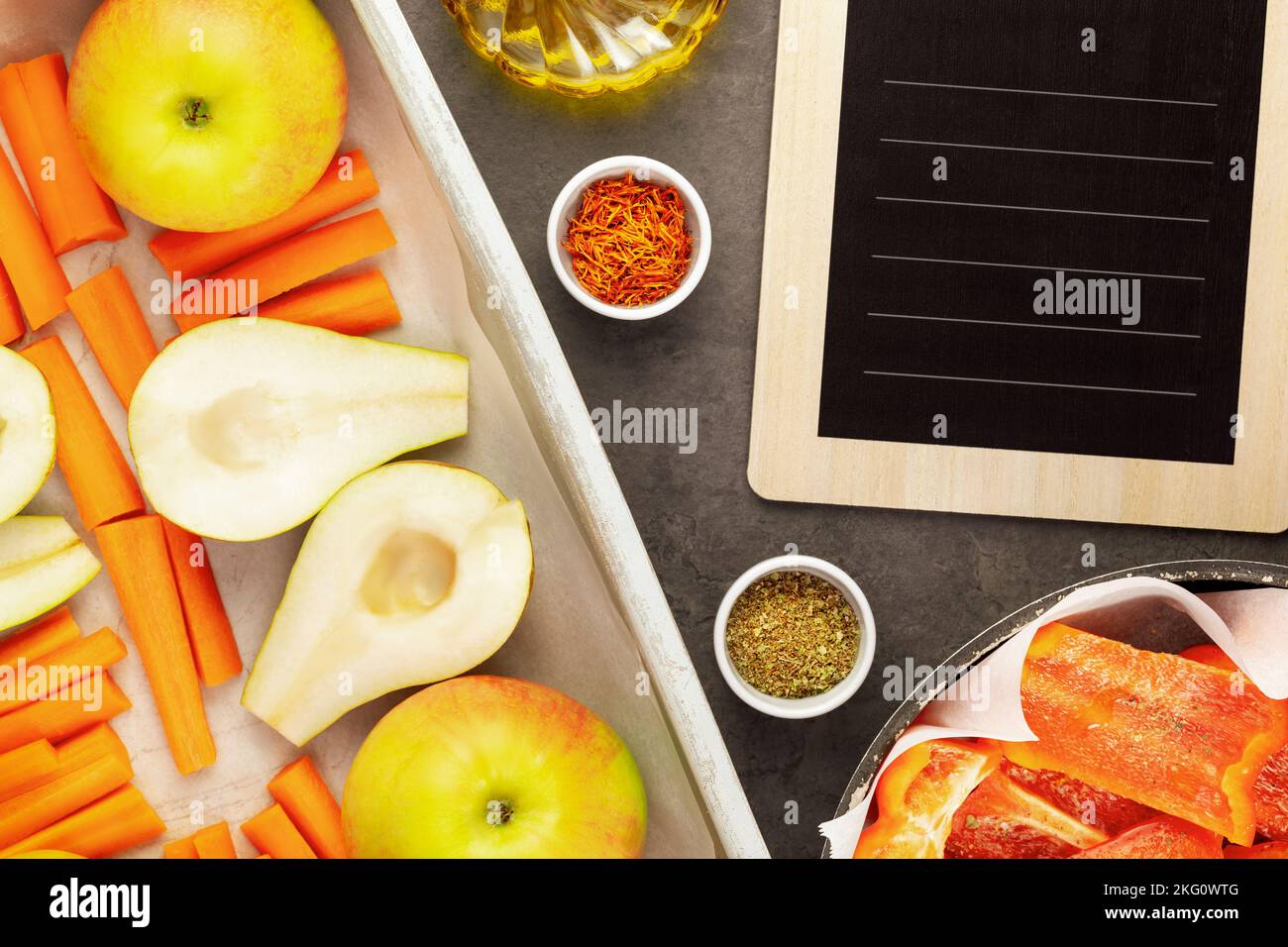 Empty black board with fresh vegetables and fruits on baking trays with ...