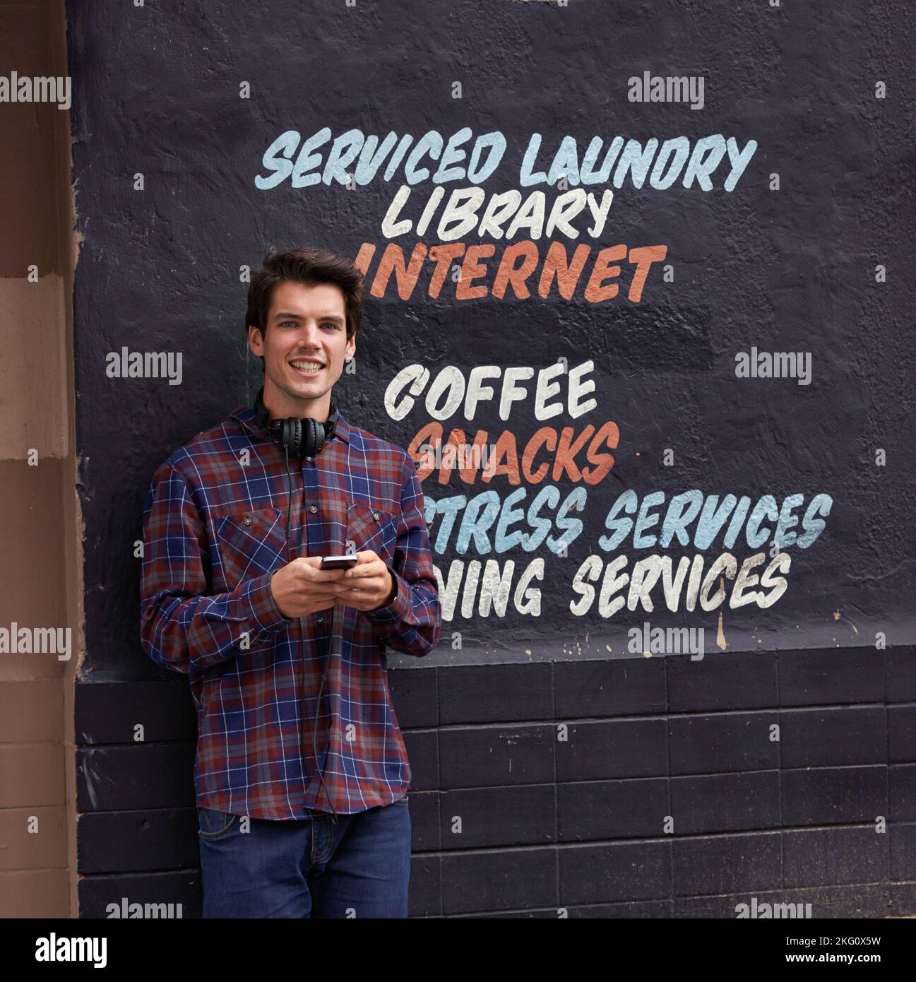 Here for your laundry needs. a young man standing outside a laundromat ...