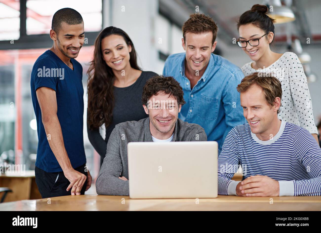 Sharing time online. a group of colleagues using a laptop together in a ...