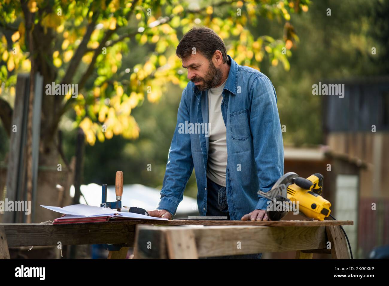 Handyman measuring a board, outside in garden Stock Photo - Alamy