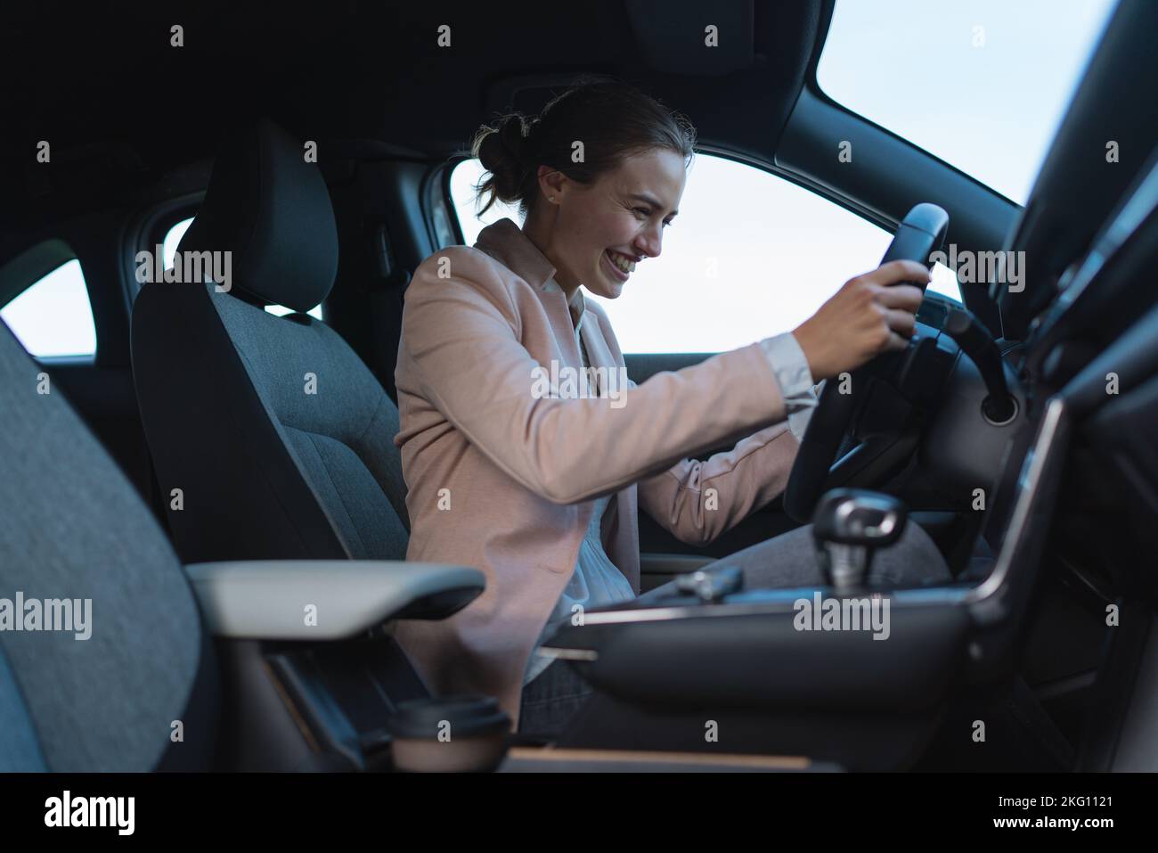 Excited young woman driving her electric car Stock Photo - Alamy