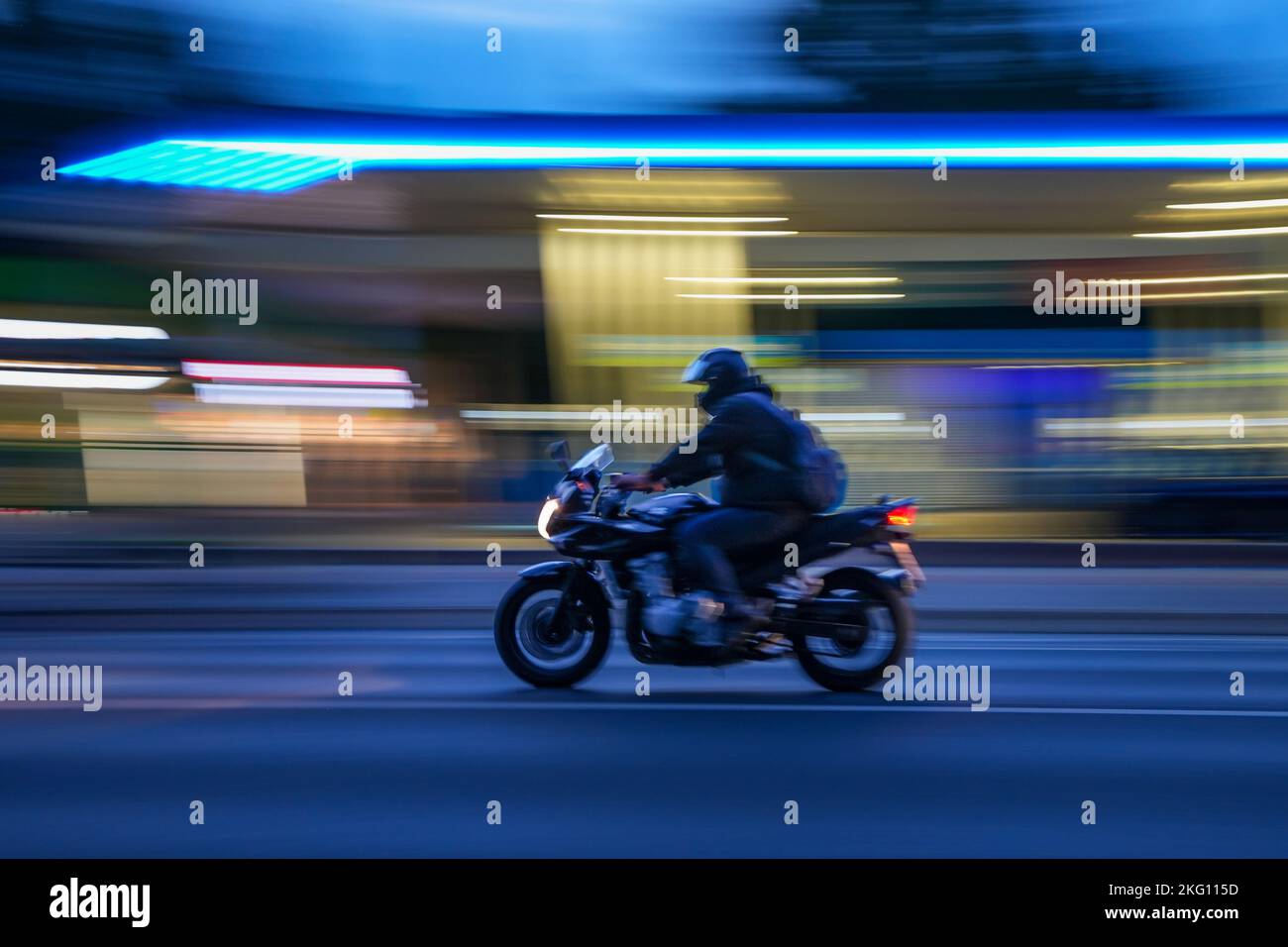 A fast-moving motorcycle in the street at night with blurred gas ...