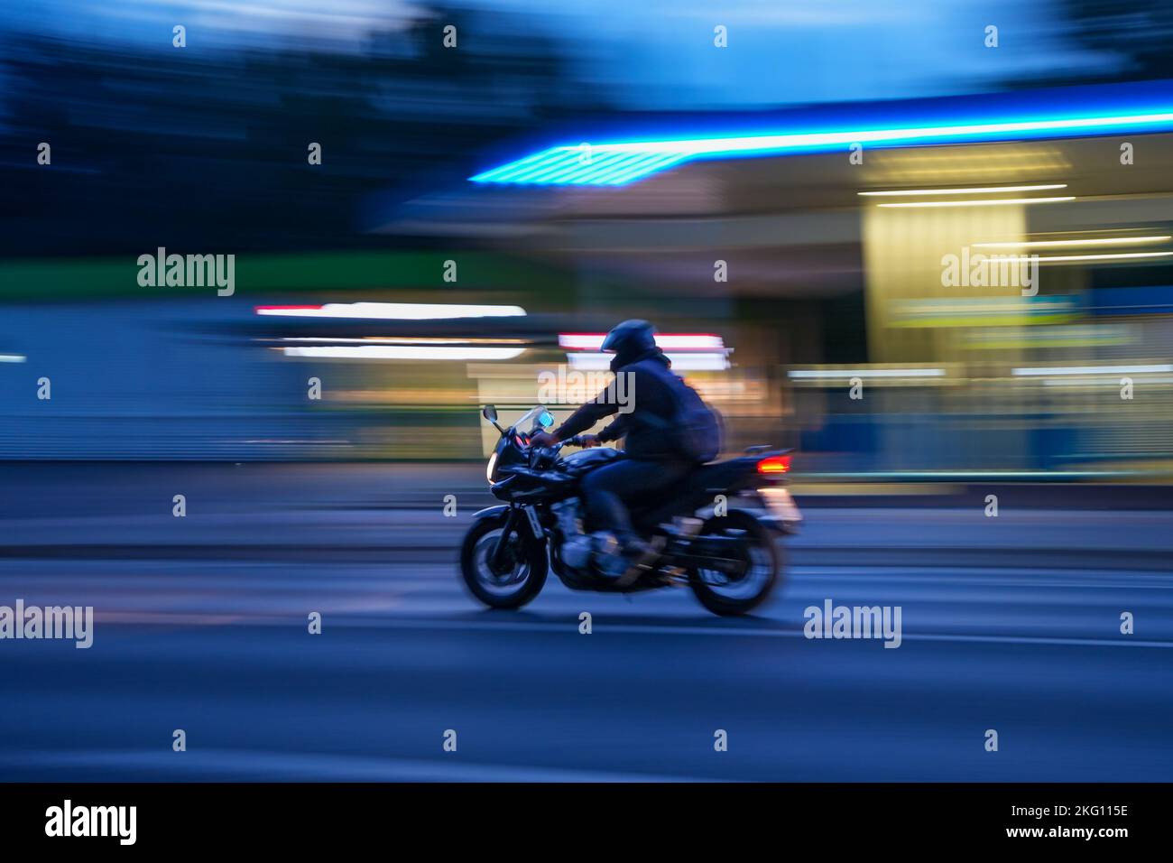 A fast-moving motorcycle in the street at night with blurred gas ...