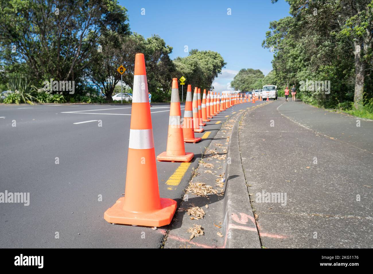 Orange traffic cones along the road, blurred people walking on the ...