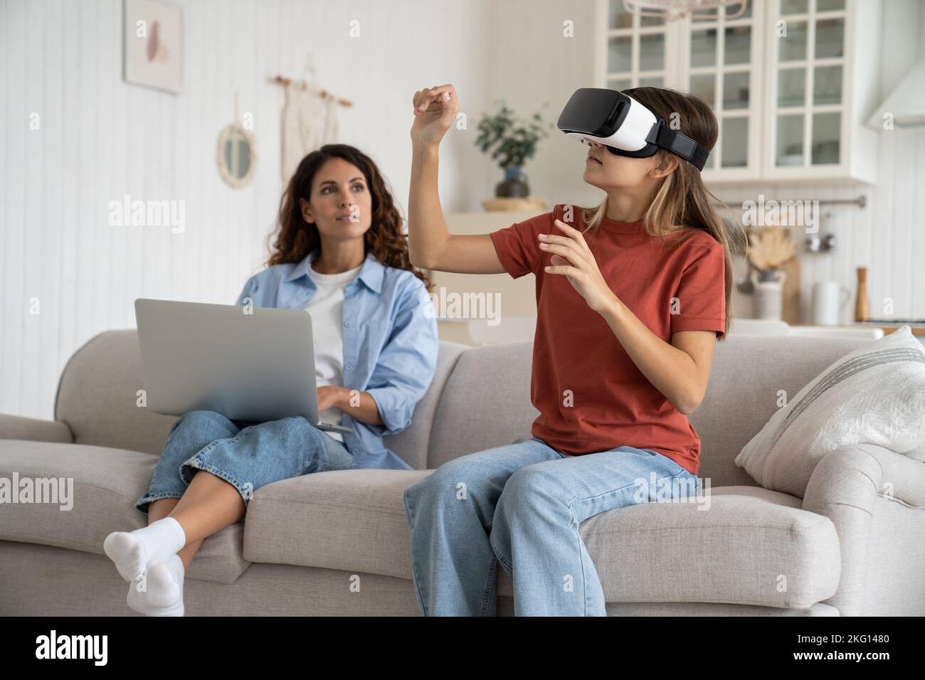 Curious teen girl using vr headset for study while mother working ...