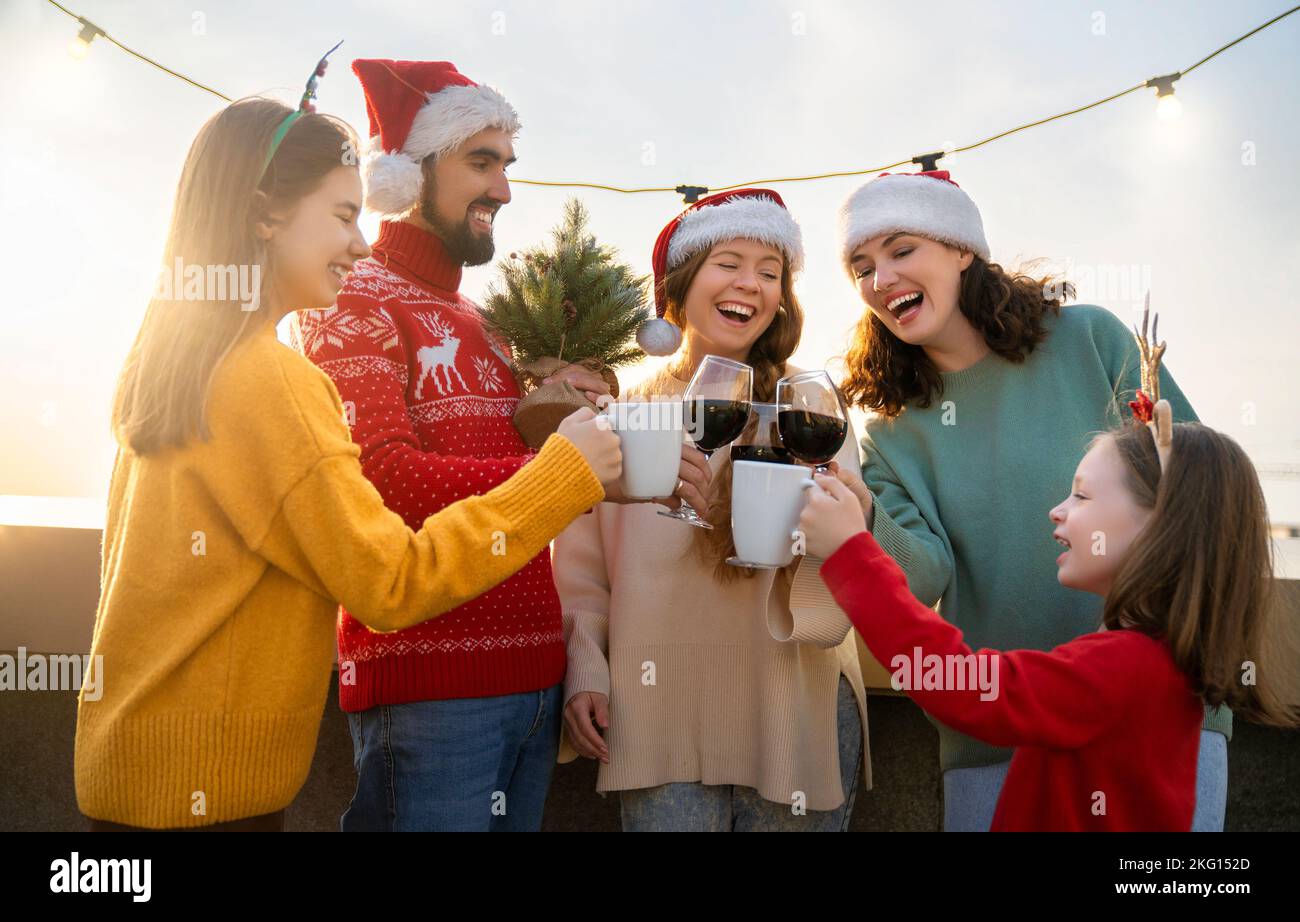 Happy friends are celebrating Christmas outdoors. Adults and kids are ...