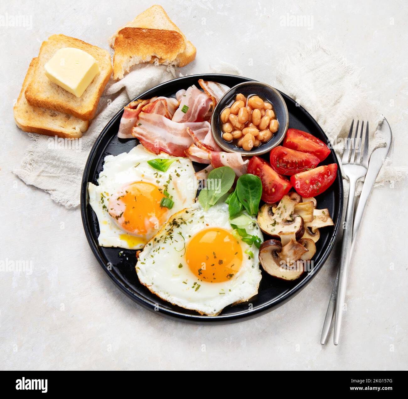 Full English breakfast with fried egg, sausage, bacon and toast on grey ...