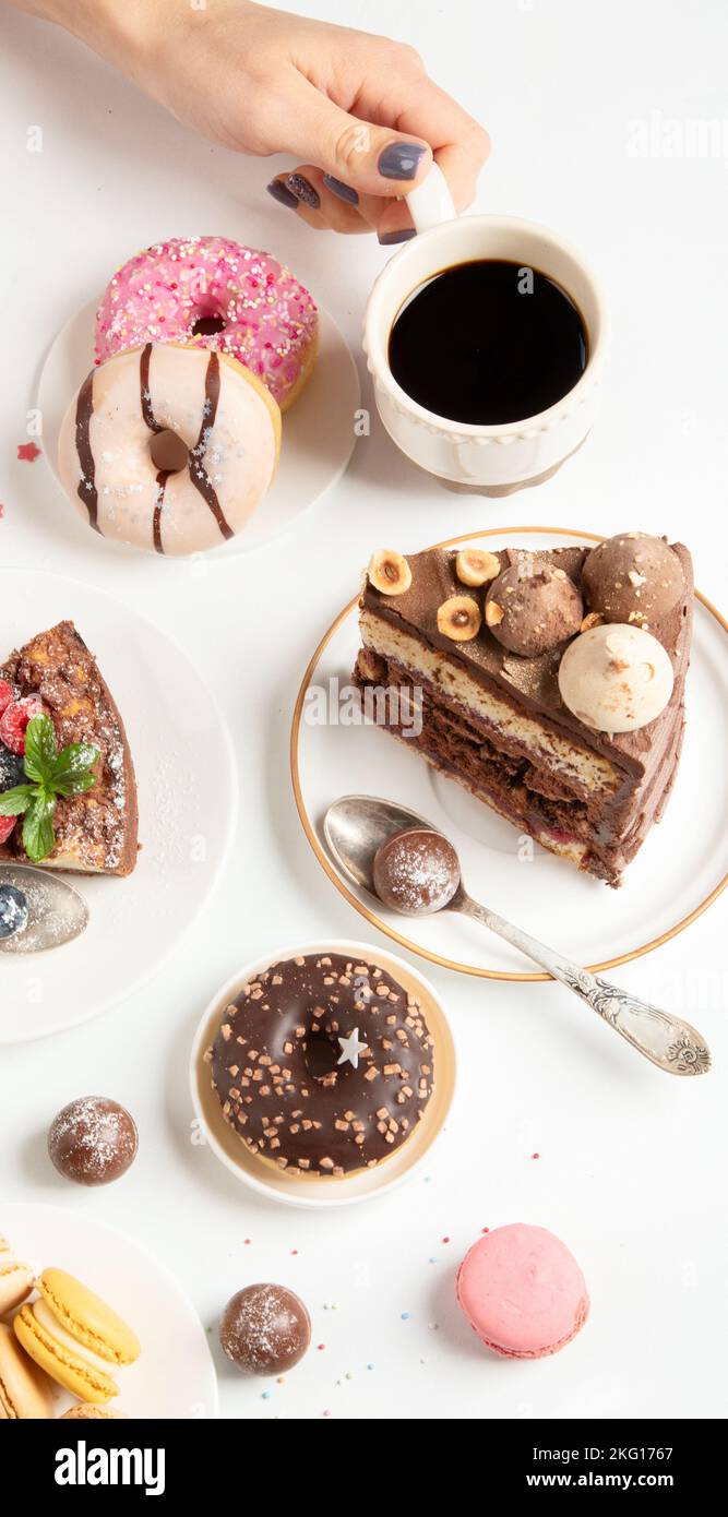 Table with various cookies, donuts, cakes, cheesecakes and coffee cups ...
