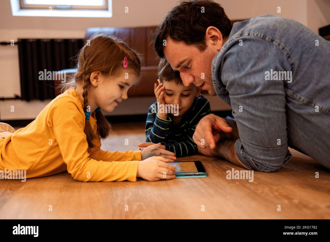 Caring young father with little daughter and son, lying together on ...