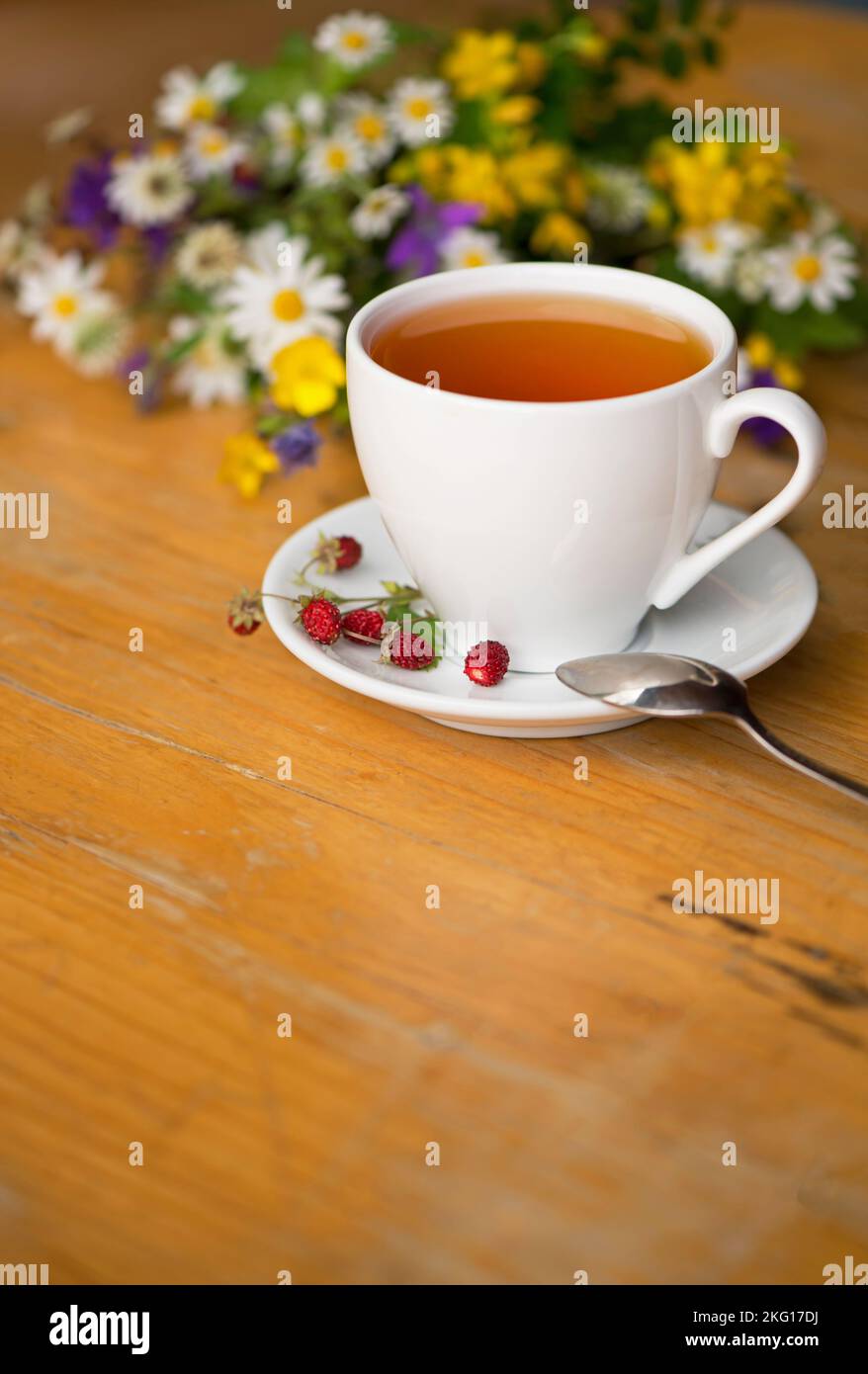cup of tea, wild strawberry, bouquet of wild flowers on a wooden ...
