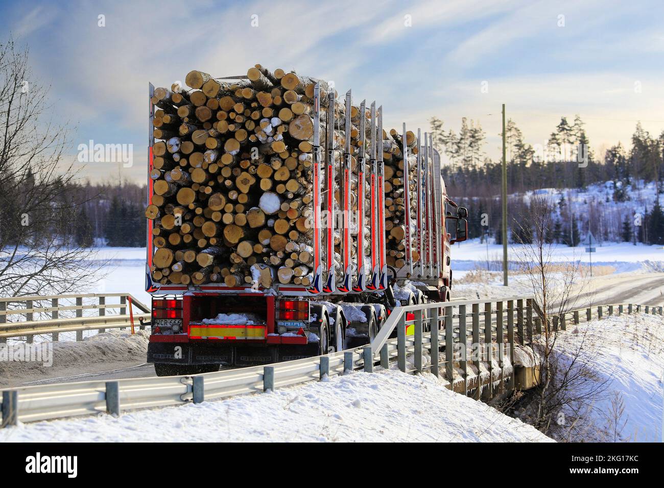 Heavy truck pulls timber trailer of birch log load on a small bridge ...