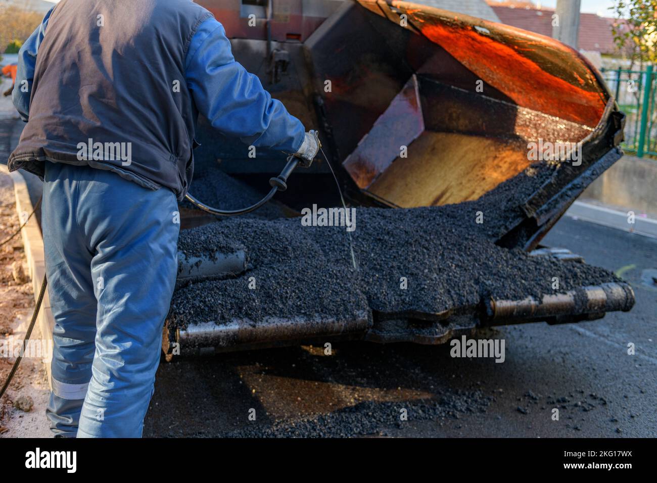 Road construction background. Worker spraying water on fresh paving ...