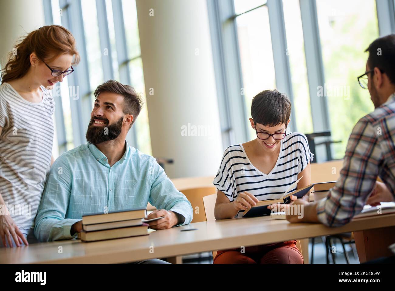 Happy university students studying with books in library. Group of ...