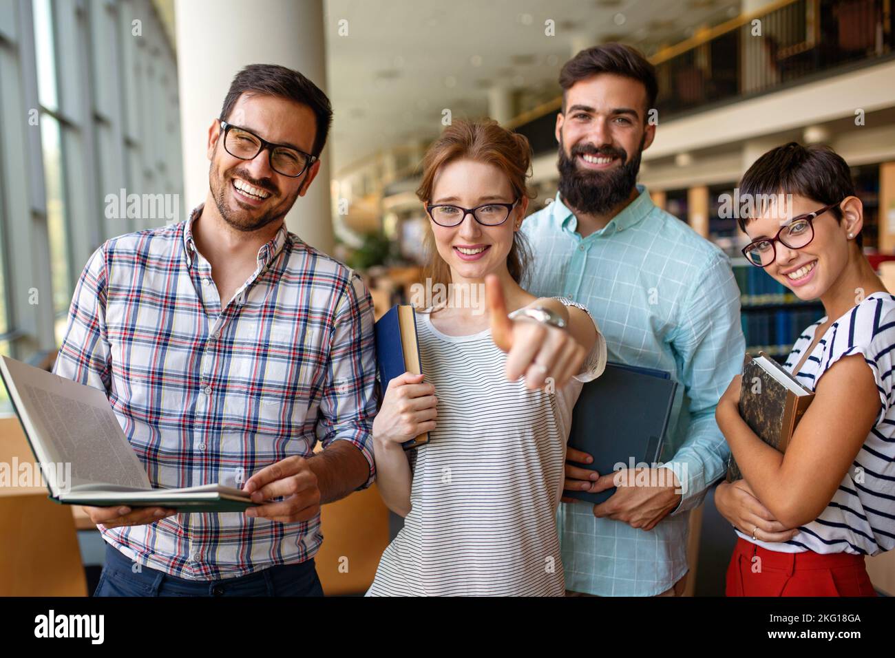 Happy university students studying with books in library. Group of ...