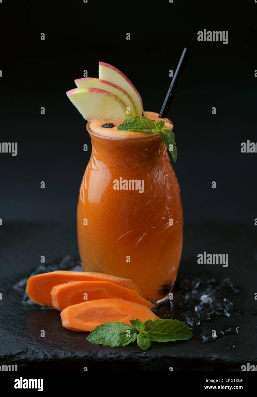 carrot juice in a glass jar with pieces of fruit on a wooden table ...
