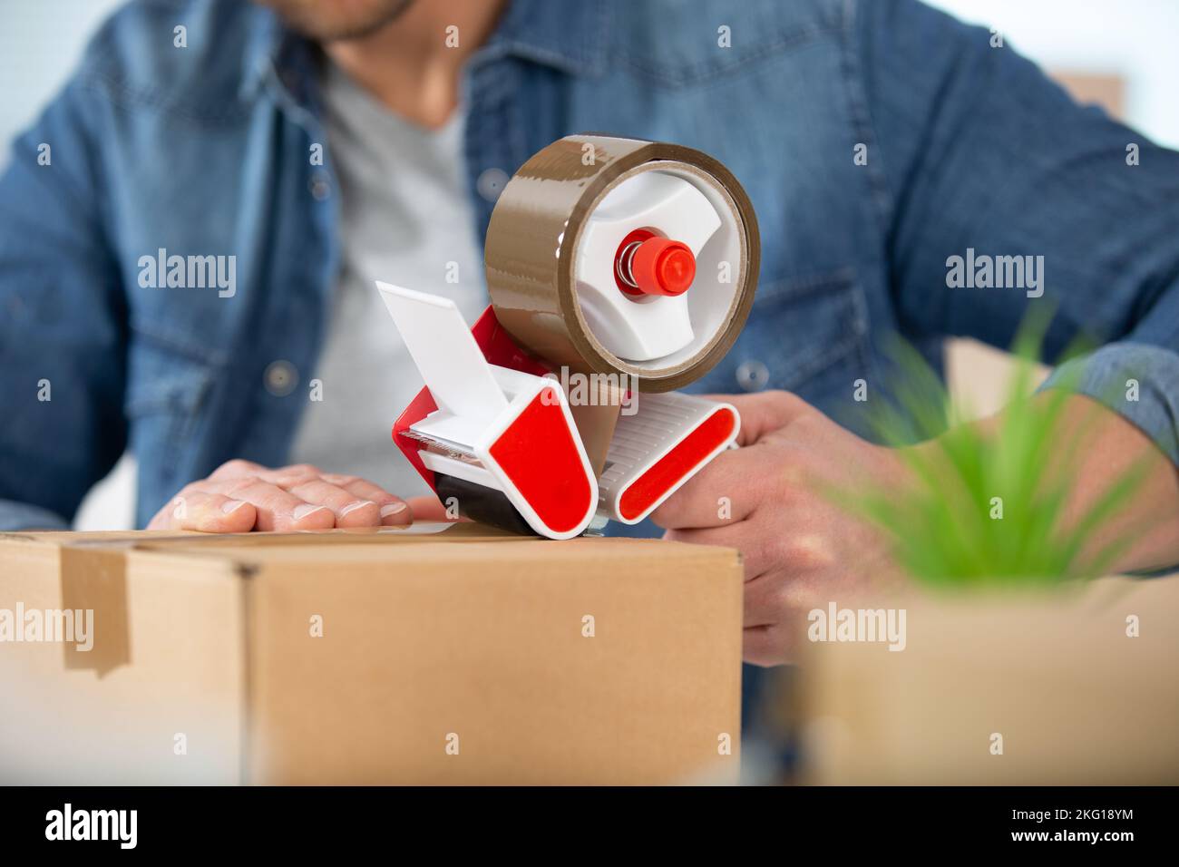 close view of man using a parcel tape dispenser Stock Photo - Alamy