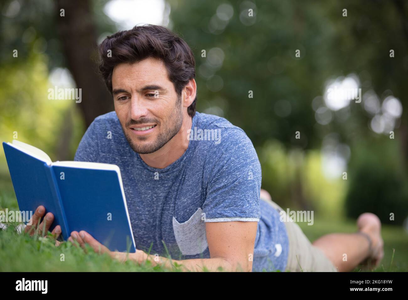 young man reading book in the park Stock Photo - Alamy