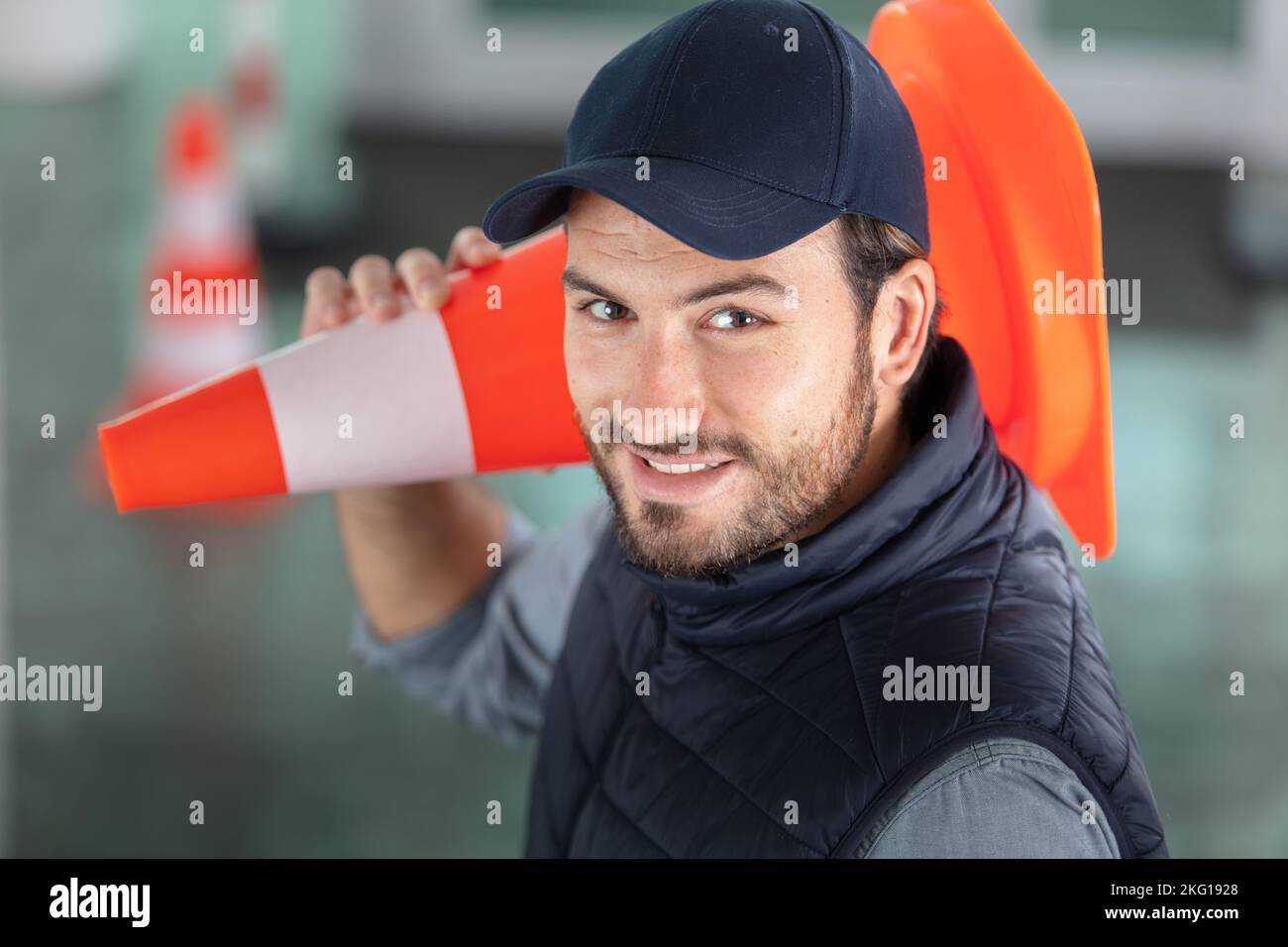 man carrying a safety cone on his shoulder Stock Photo - Alamy