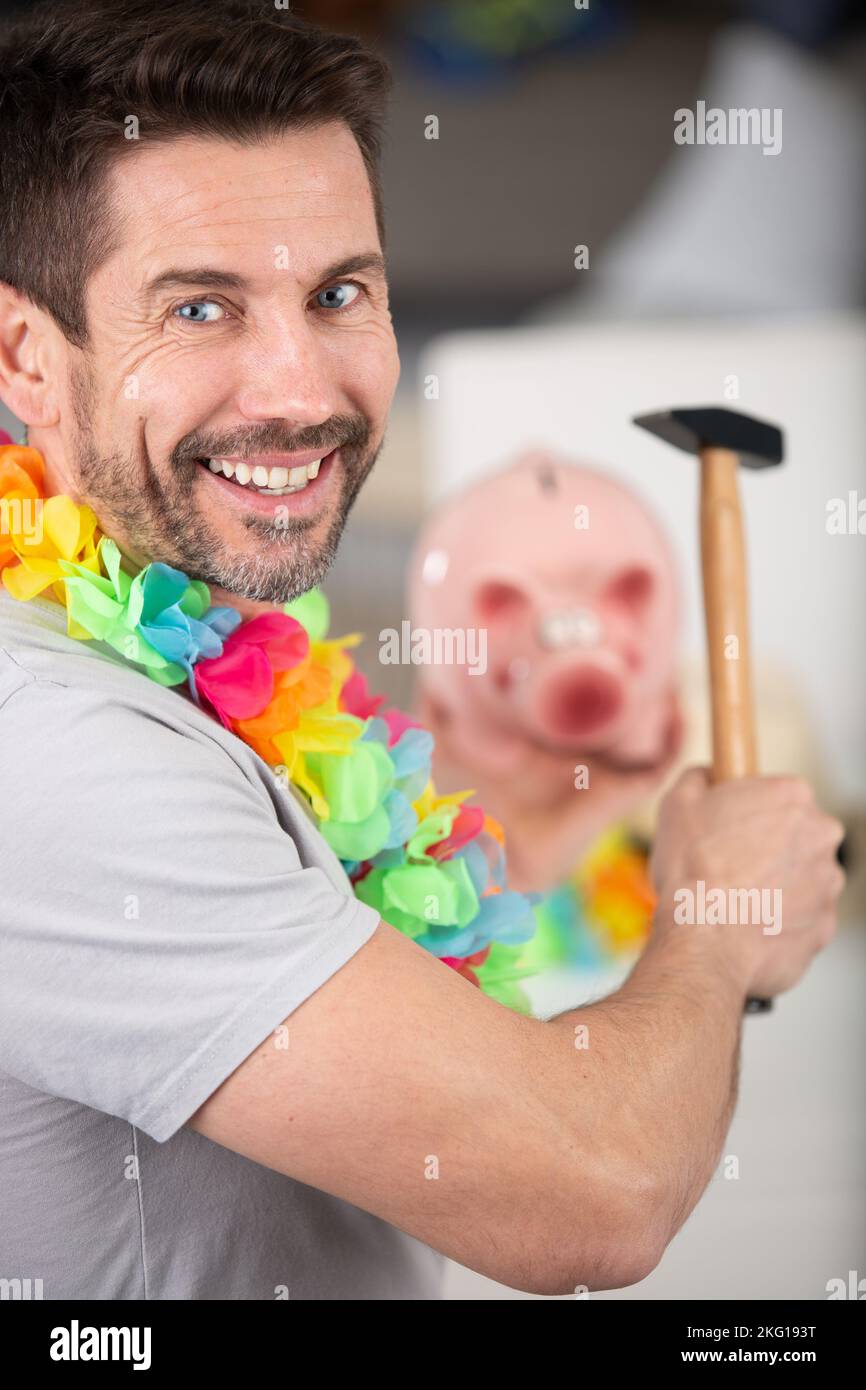 happy man breaking piggy bank with hammer Stock Photo - Alamy
