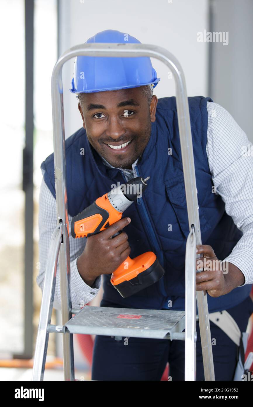 happy male builder standing on ladder with drill Stock Photo - Alamy