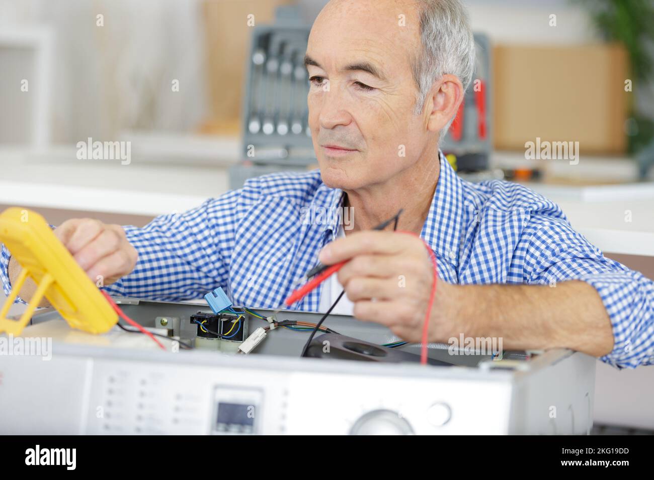 senior man checking washing machine with multimeter Stock Photo - Alamy