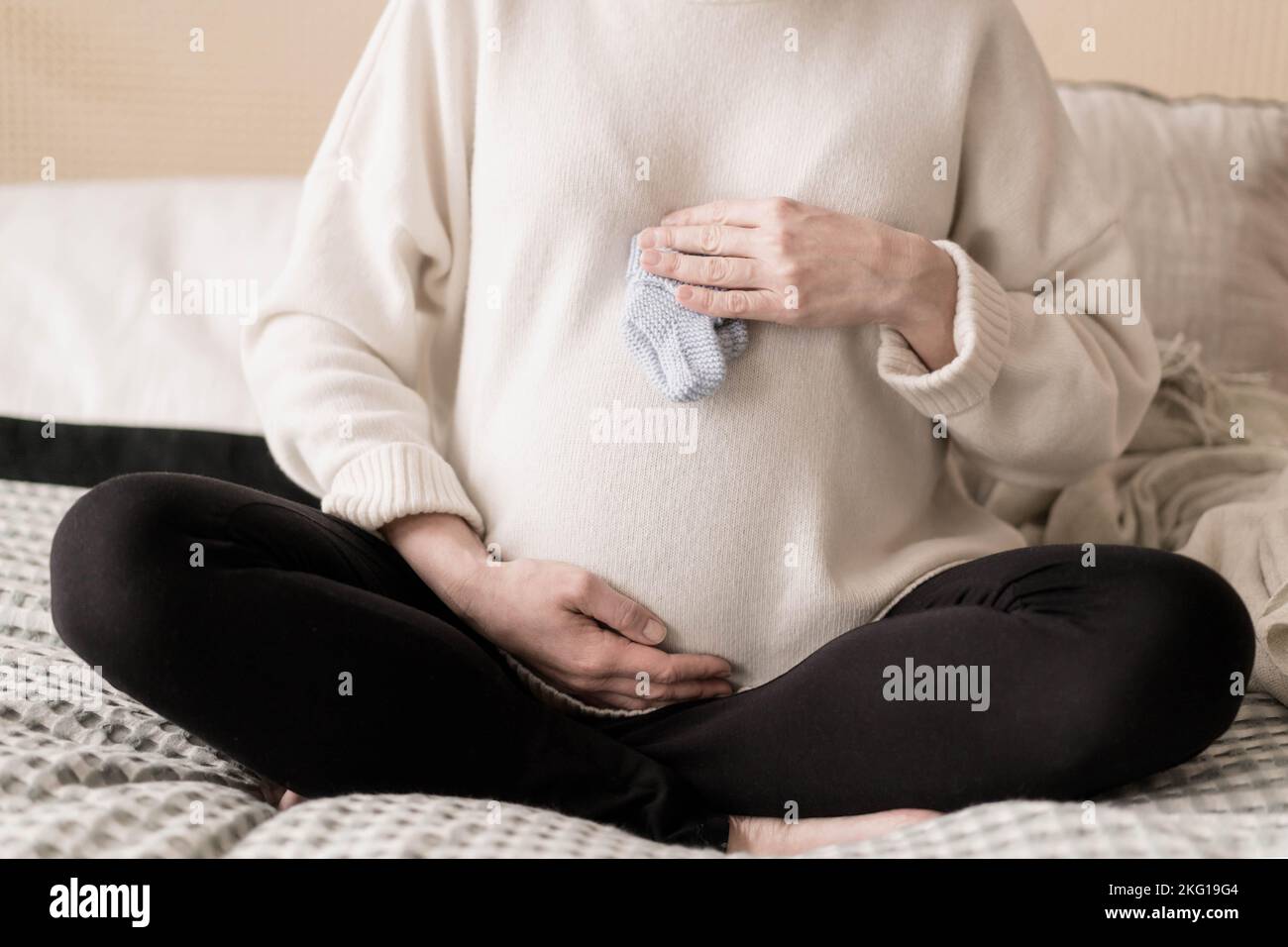 A pregnant woman in a warm knitted sweater and holding her belly. Soft ...