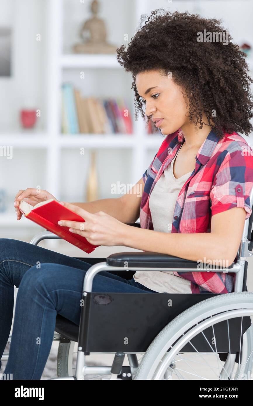 young lady in wheelchair reading a book Stock Photo - Alamy
