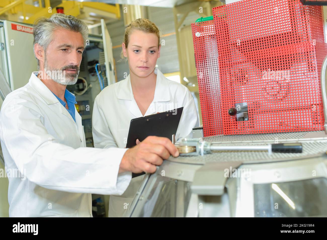 Man and woman with clipboard next to machine Stock Photo - Alamy