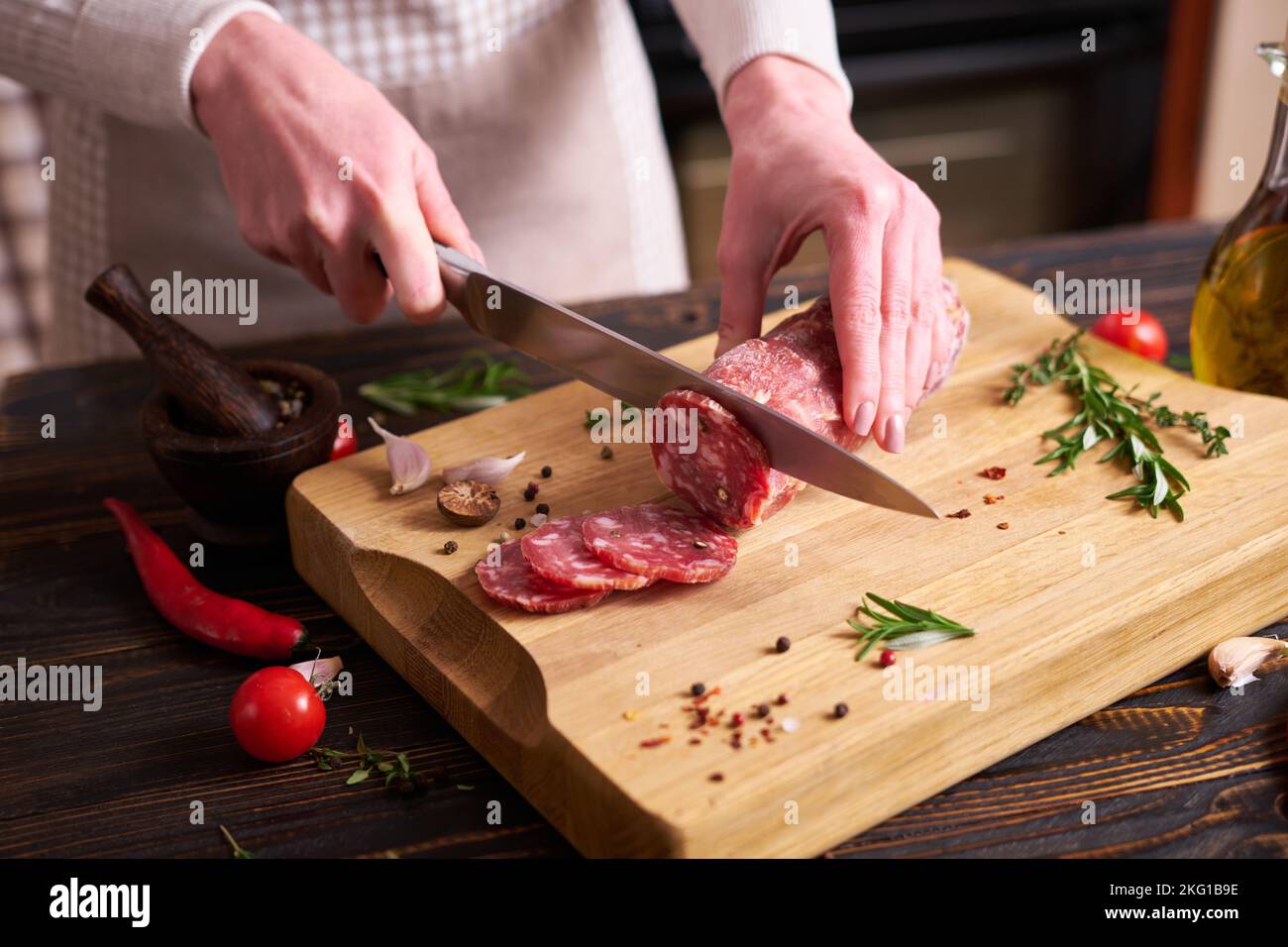 Woman slicing Traditional salami sausage on wooden cutting board by a ...
