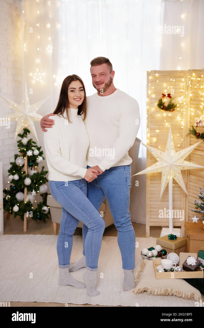 Young family couple cuddling in christmas decorated room Stock Photo ...