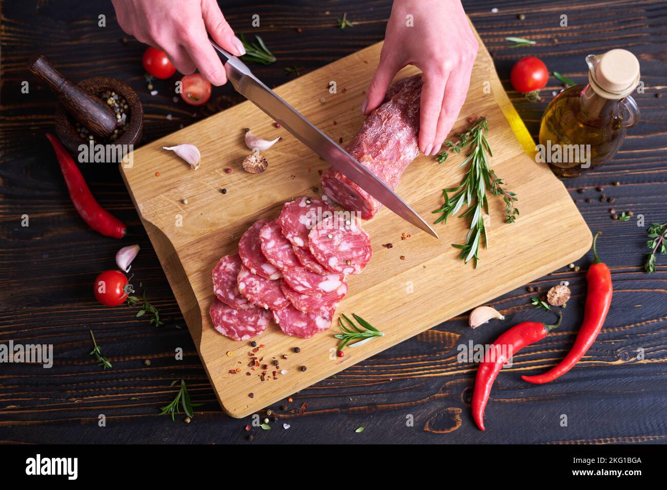 Woman slicing Traditional salami sausage on wooden cutting board by a ...