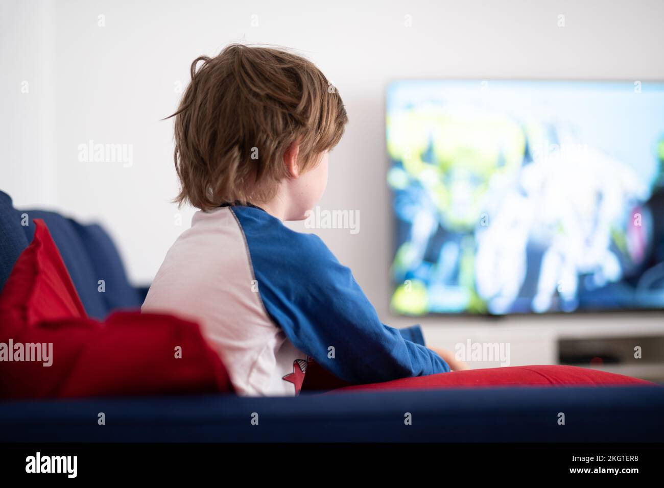 Rear view of little boy sitting on a sofa watching TV Stock Photo - Alamy