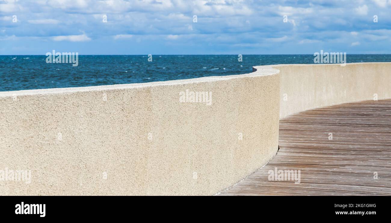 Empty promenade with wooden floor and curved concrete railing mounted ...