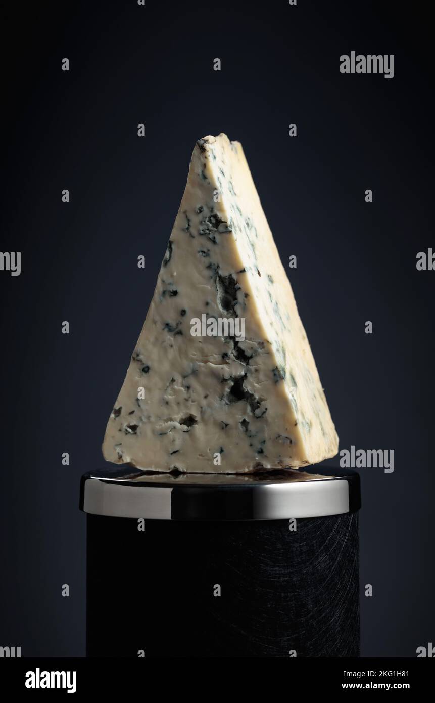 Triangle piece of blue cheese on a black background Stock Photo - Alamy