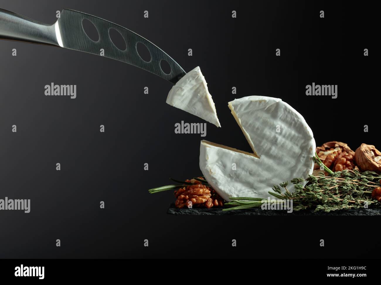 Brie cheese with walnuts, thyme, and rosemary on a black background ...