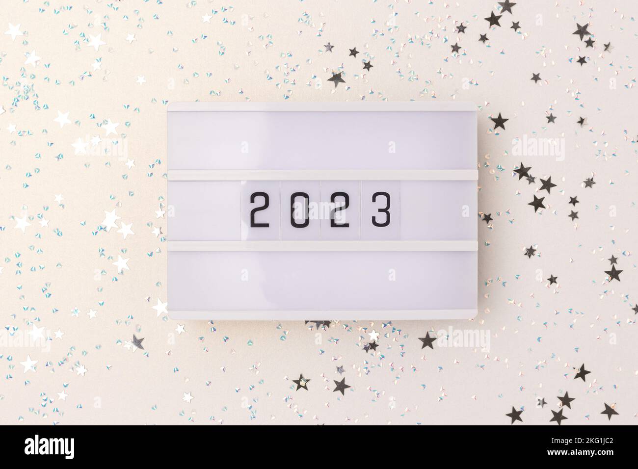 Lightbox with 2023 numbers and stars confetti scattered on a silver ...