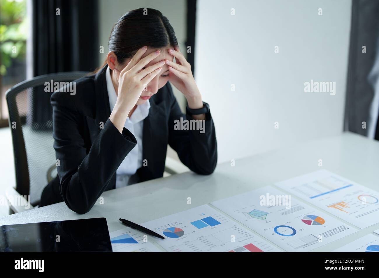 A portrait of a beautiful Asian female employee showing a stressed face ...