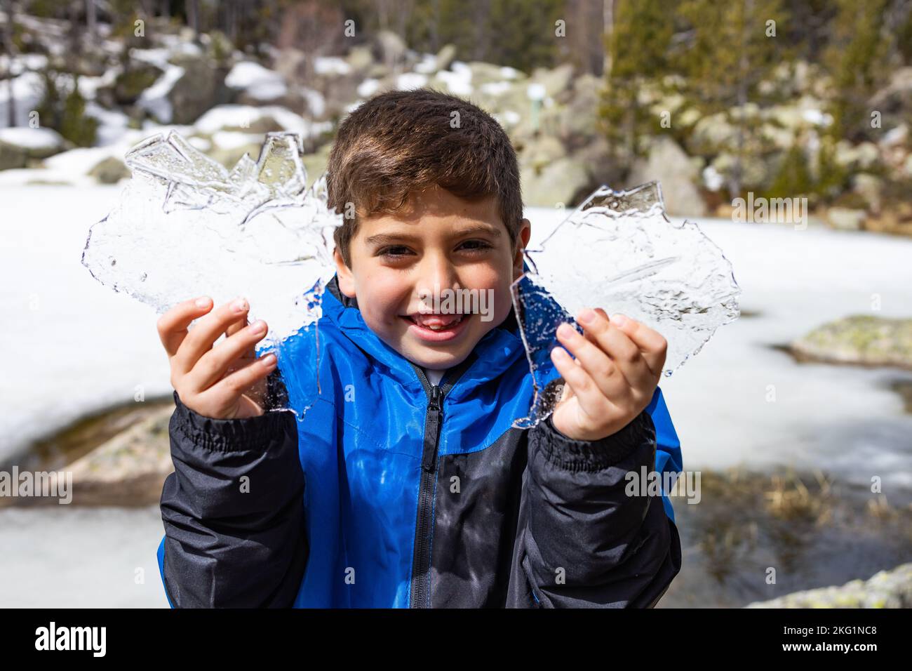 Little kid behind of a piece of ice on the forest. Focus on ice Stock ...