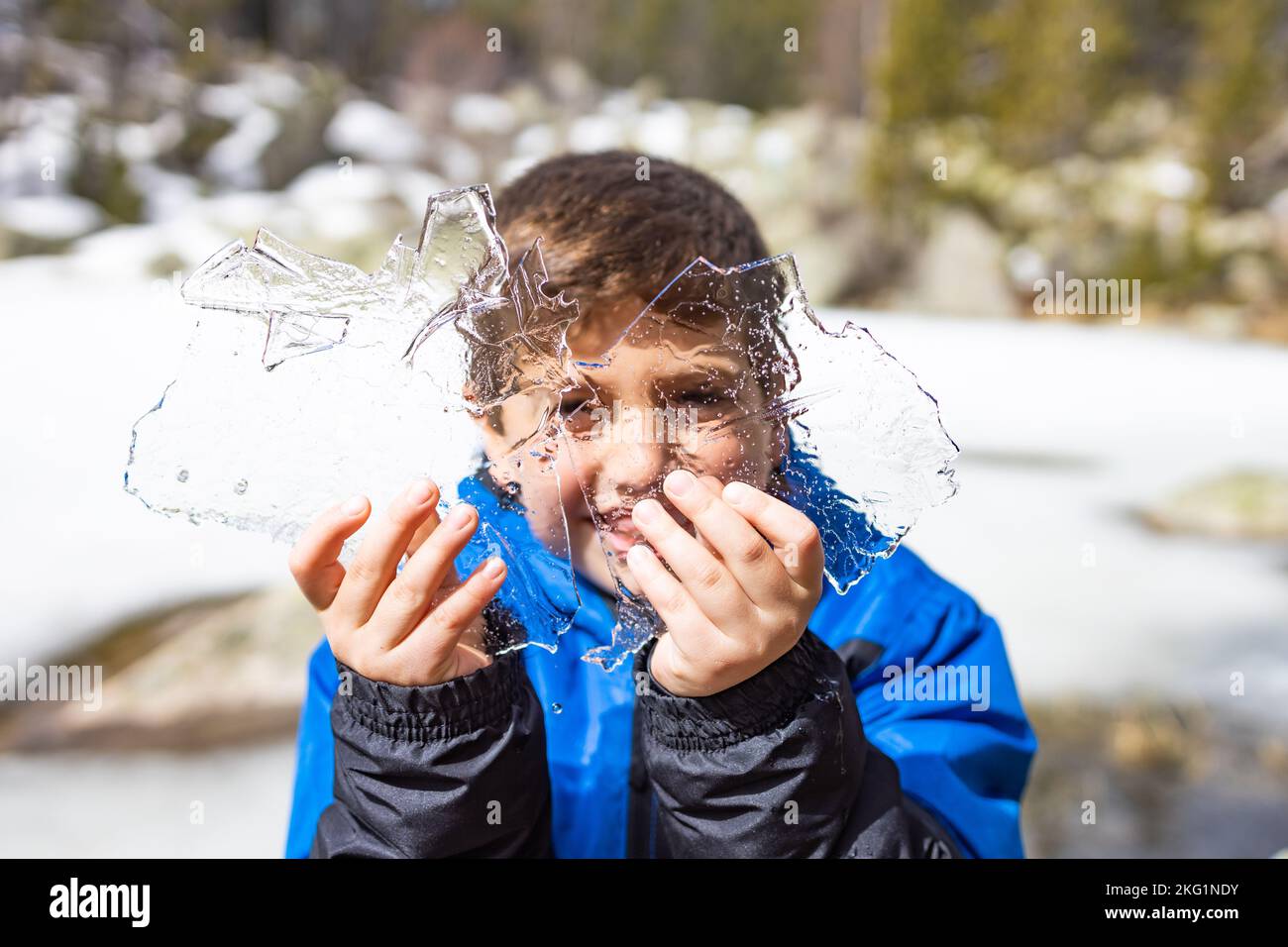 Little kid behind of a piece of ice on the forest. Focus on ice Stock ...