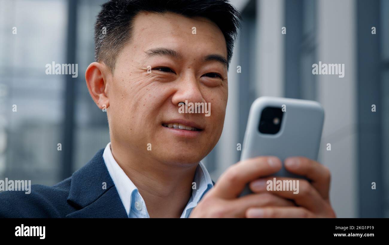 Close up male in city outdoors looking phone screen Asian 40s ... Close up male in city outdoors looking phone screen Asian 40s ...