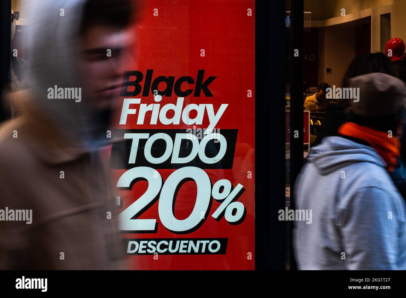 People walk passing by a sign that announces a price discount for Black ...