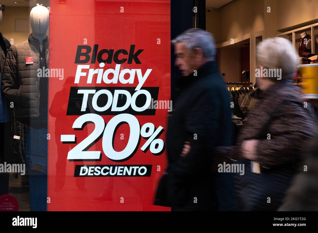 People walk passing by a sign that announces a price discount for Black ...