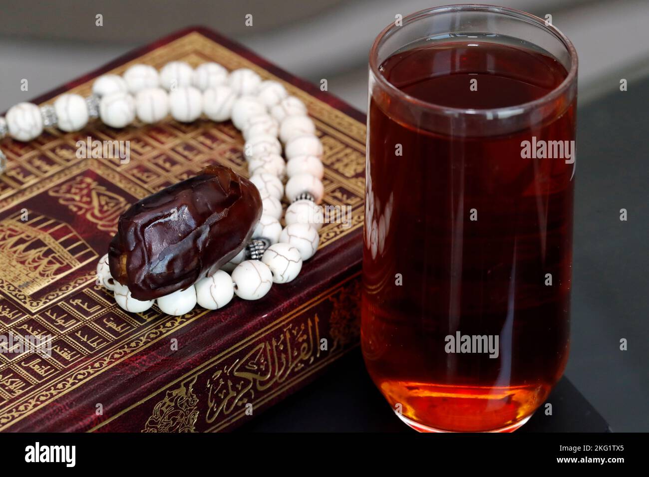 Holy Quran in arabic, muslim prayer beads, glass of tea and fresh date ...