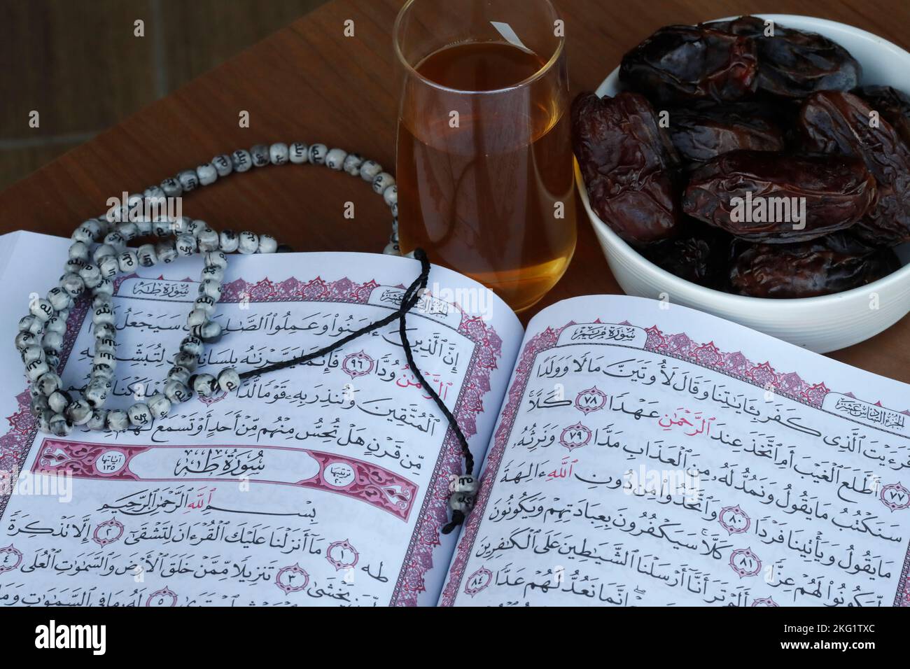 Holy Quran in arabic, muslim prayer beads, glass of tea and fresh dates ...