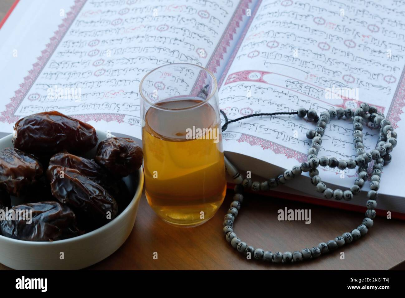 Holy Quran in arabic, muslim prayer beads, glass of tea and fresh dates ...