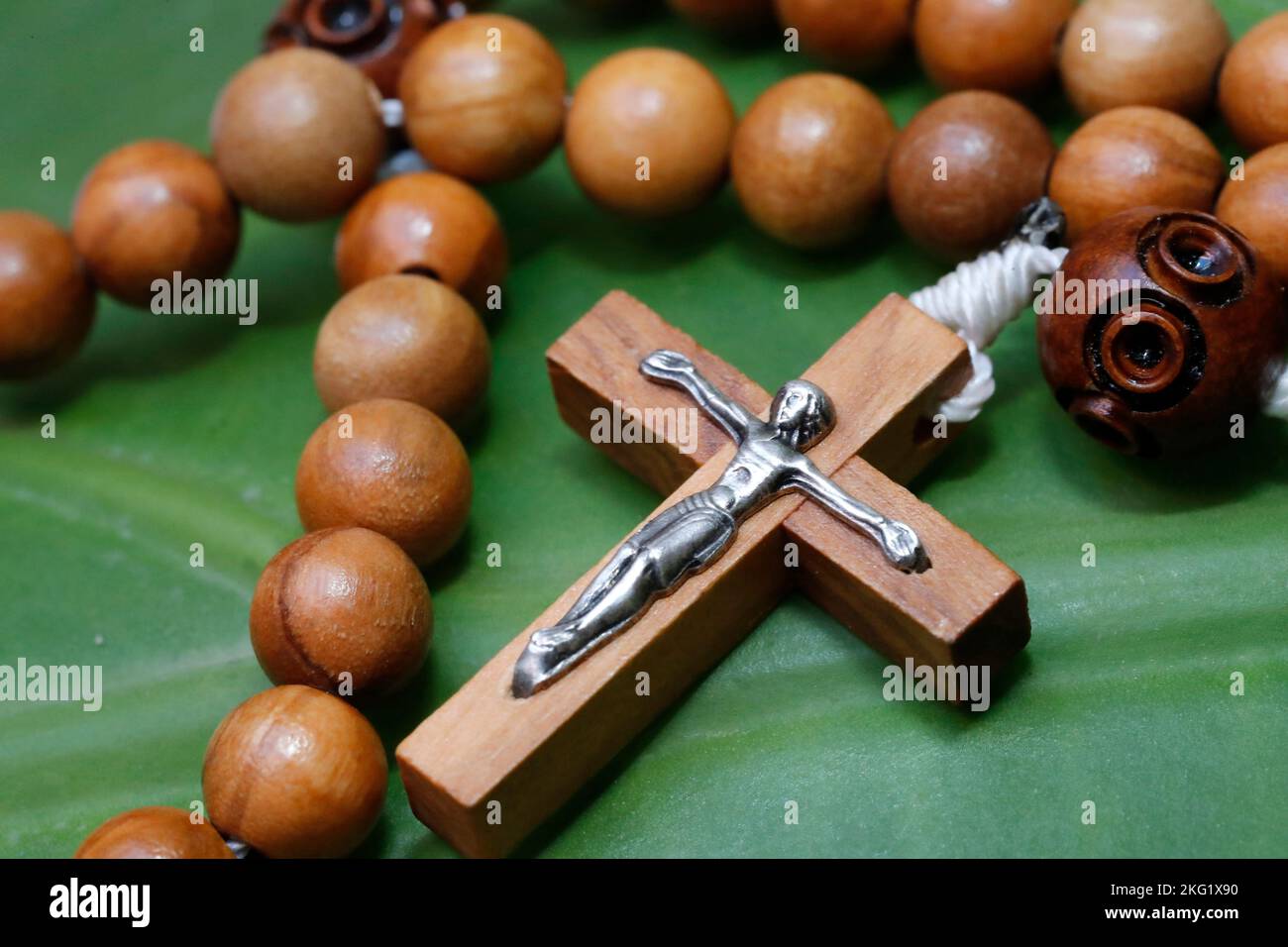 A wooden rosary on a green leave. Symbol of christianity Stock Photo ...